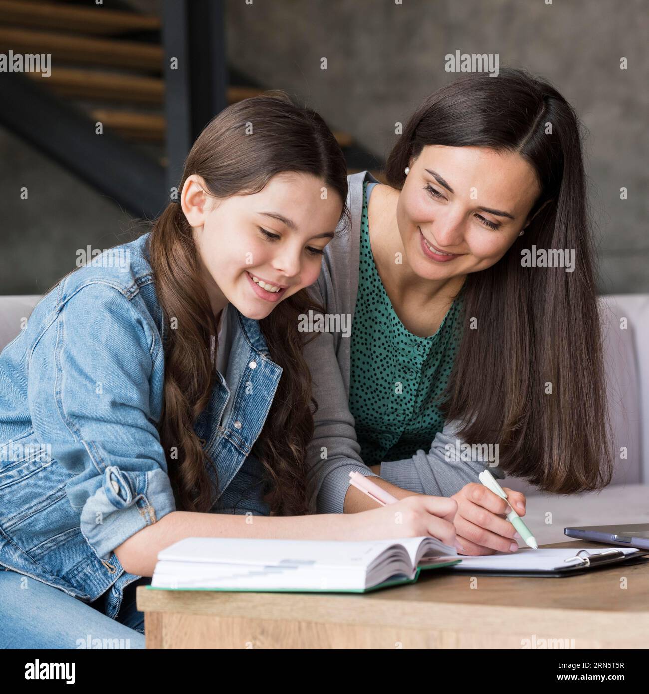 Mom doing homework with daughter Stock Photo - Alamy