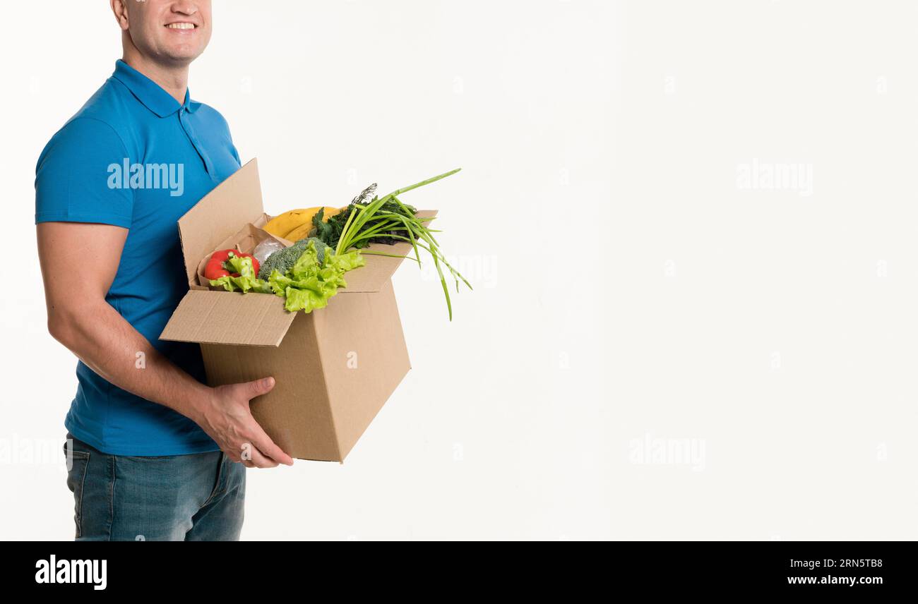 Side view delivery man posing with grocery box Stock Photo - Alamy