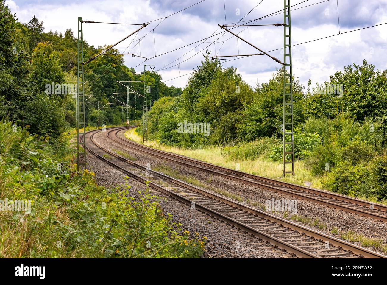 An electrified railroad track through green nature in rural Bavaria ...