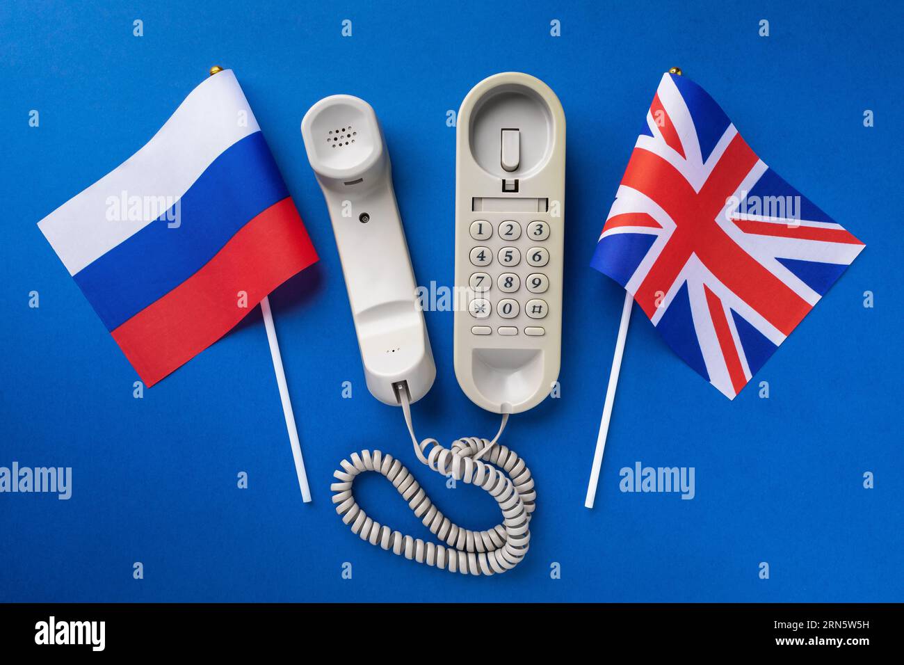 An old telephone and two flags on a blue background, a concept on the ...