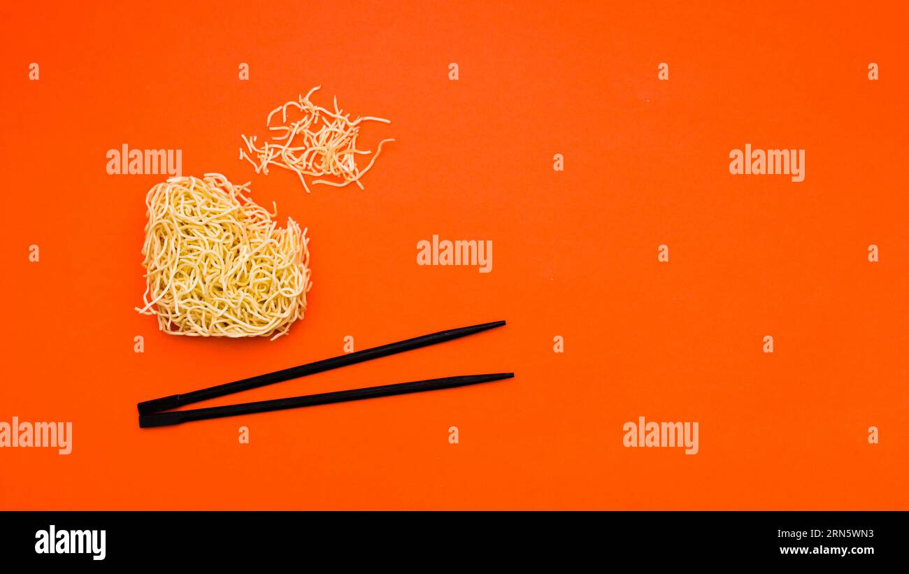 Broken dry instant noodles with chopsticks orange background Stock ...