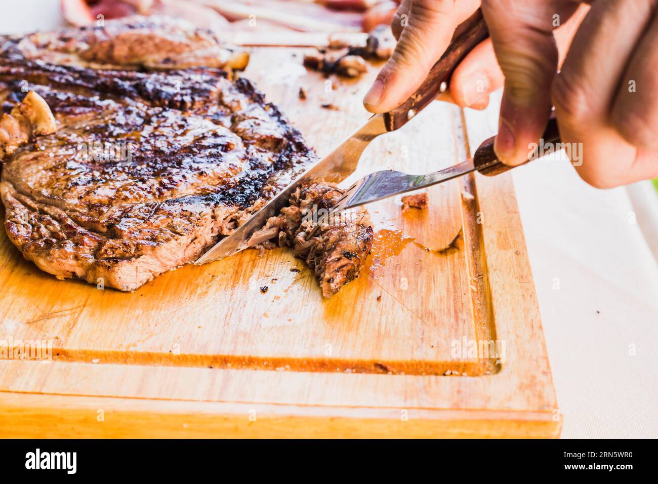 Close up person s hand slicing meat with fork knife Stock Photo - Alamy