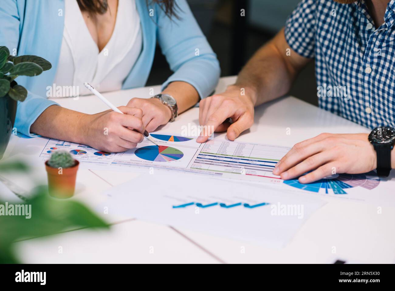Crop people comparing data chart Stock Photo - Alamy