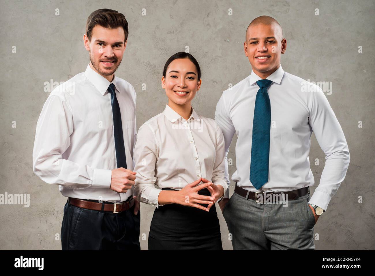 Successful young business partners looking camera standing against grey ...