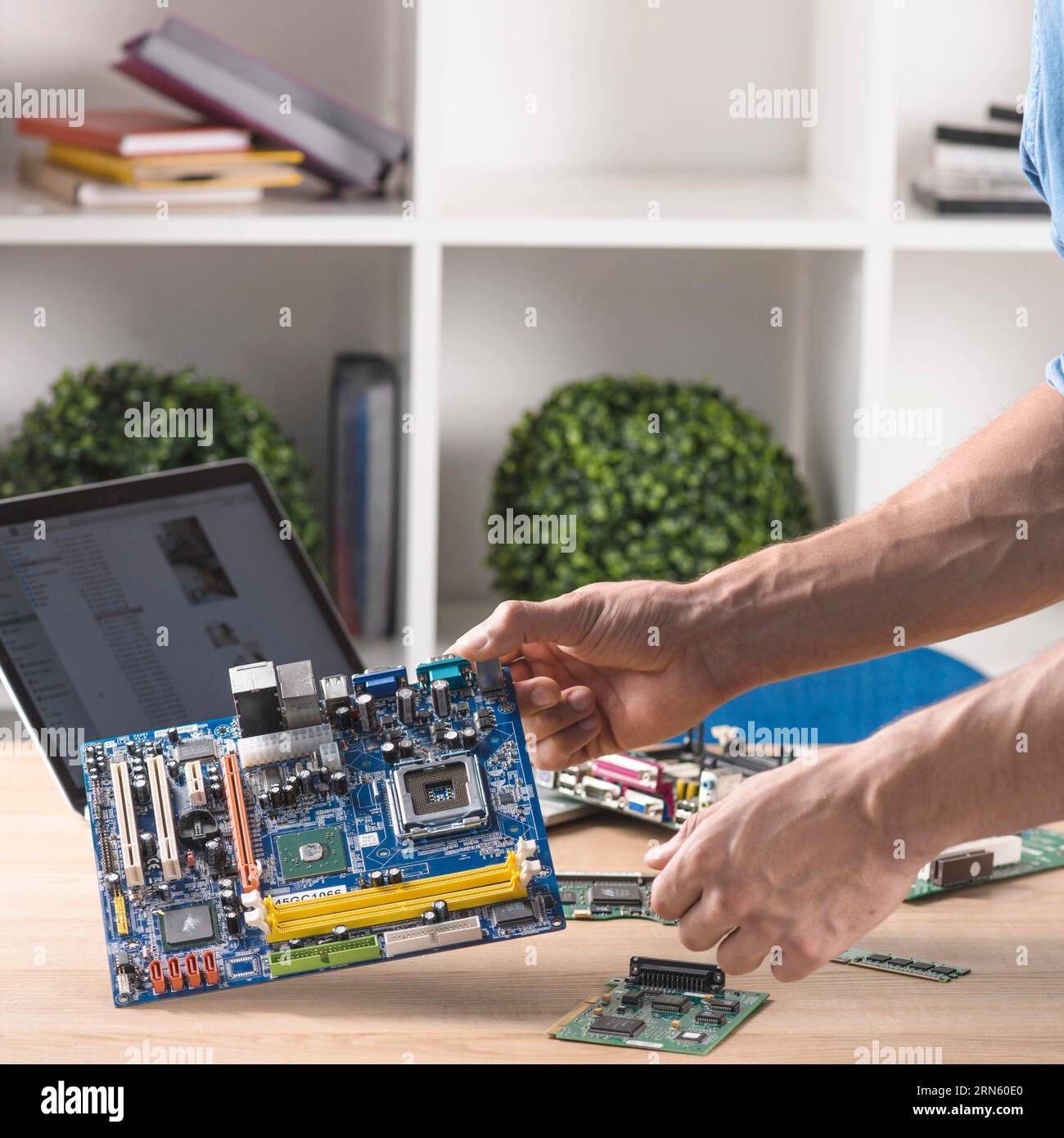 Close up male technician holding modern computer motherboard from table ...