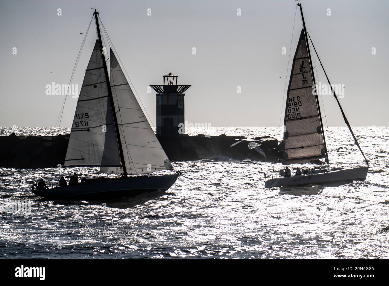 Sailing boat leaving the harbour of Scheveningen, beacon at the harbour ...
