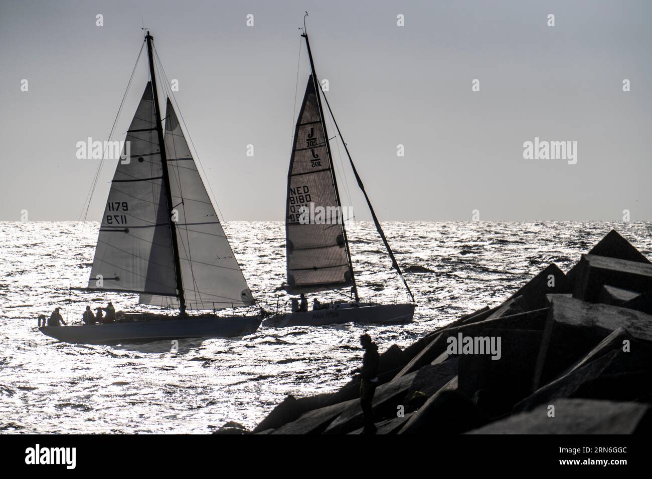 Sailing boat leaving the harbour of Scheveningen, beacon at the harbour ...