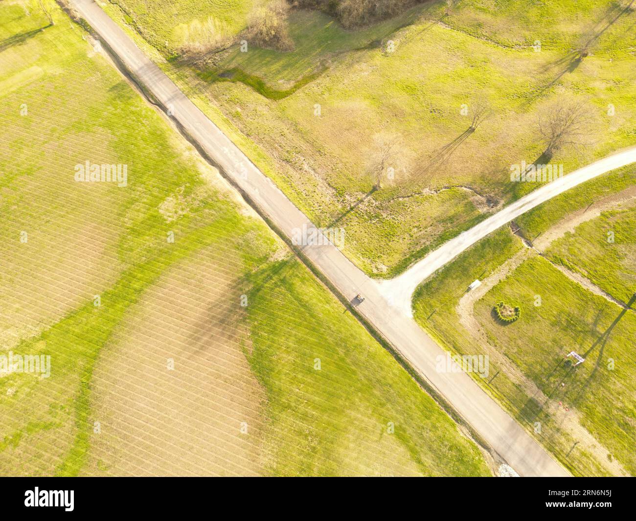 A scenic rural landscape featuring a wide open field next to a road ...