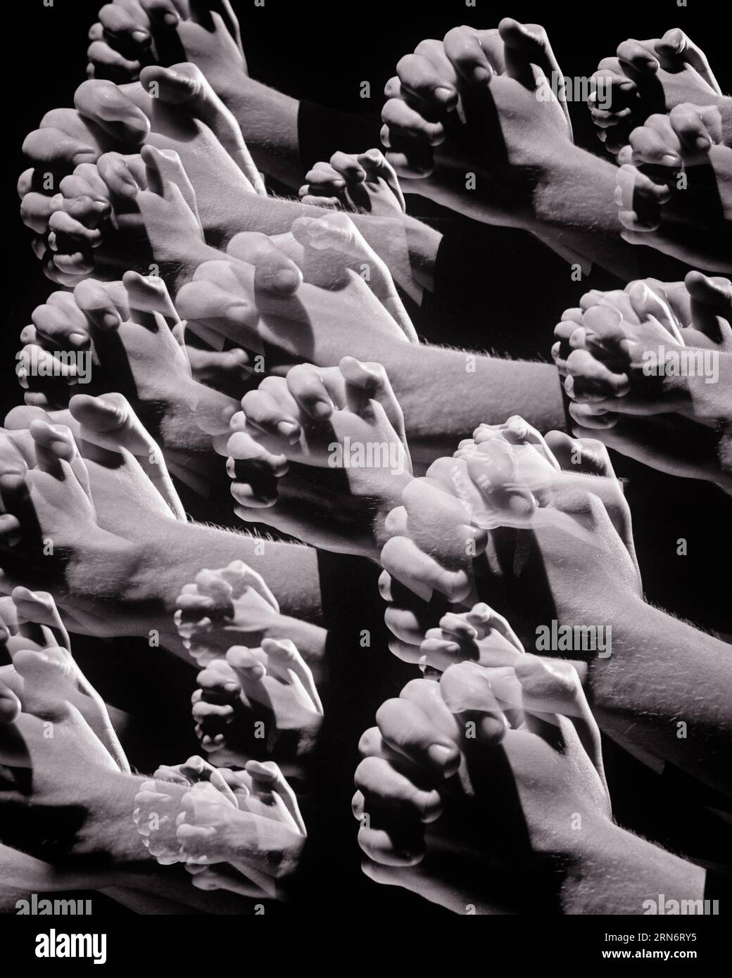 1960s COMPOSITE OF SEVERAL TIGHTLY CLASPED CLINCHED ADULT MALE HANDS ...