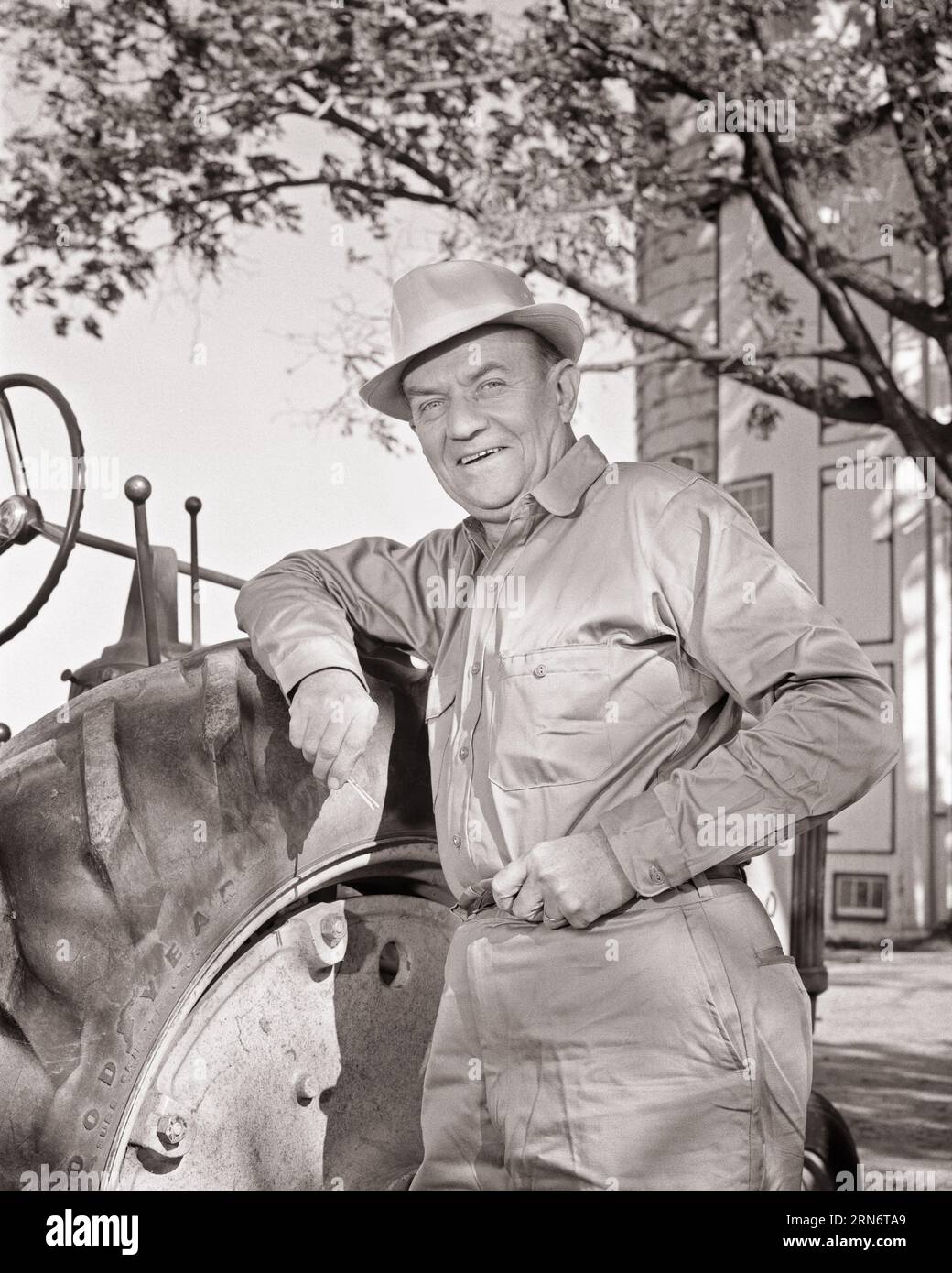 1960s PORTRAIT FARMER A SENIOR MAN LEANING ON LARGE TIRE OF TRACTOR ...