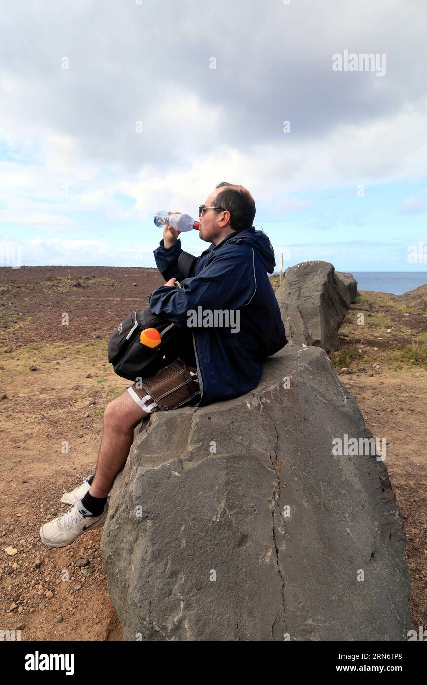 Walker sitting on a rock having a drink, path to Papagayo beach ...