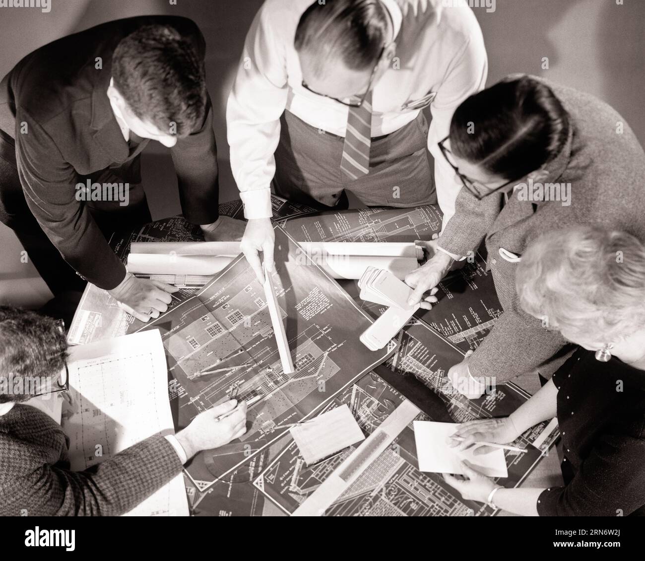 1960s GROUP MEN WOMAN LOOKING AT PLANS BLUEPRINTS HIGH ANGLE - o2701 ...