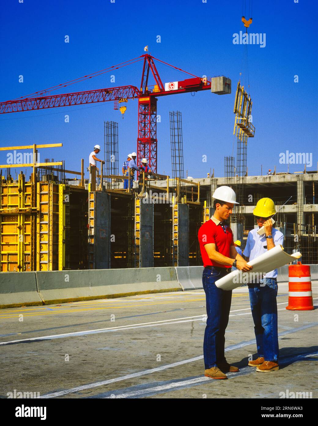 1990s CONSTRUCTION SITE TWO MEN REVIEWING PLANS WEARING HARD HATS JEANS ...