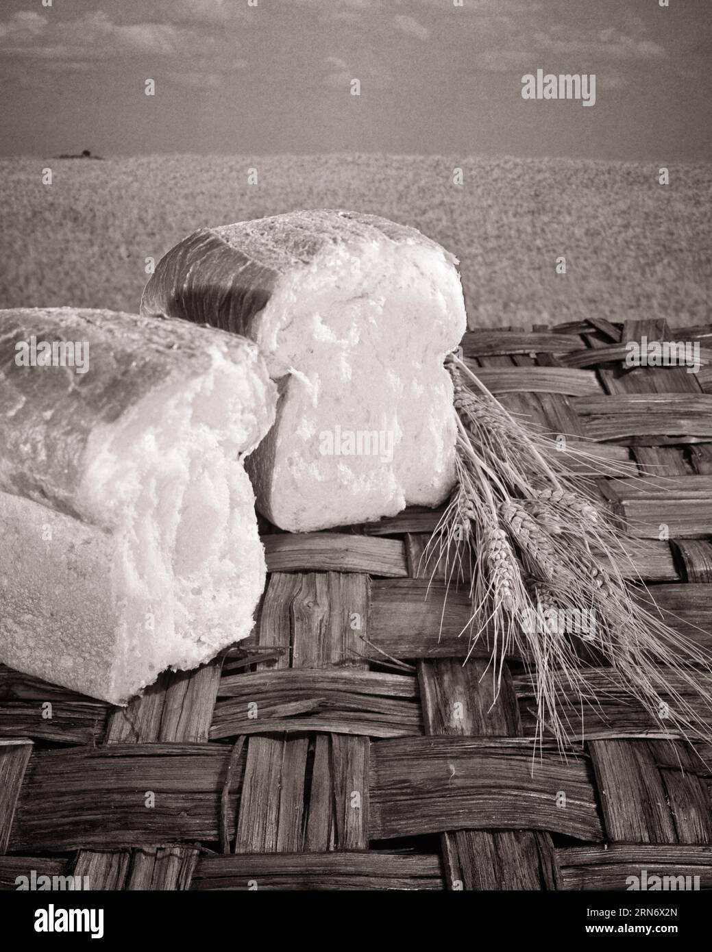 1960s LOAF OF HOMEMADE BREAD SLICED IN HALF ON WOODEN MAT WITH STALKS ...
