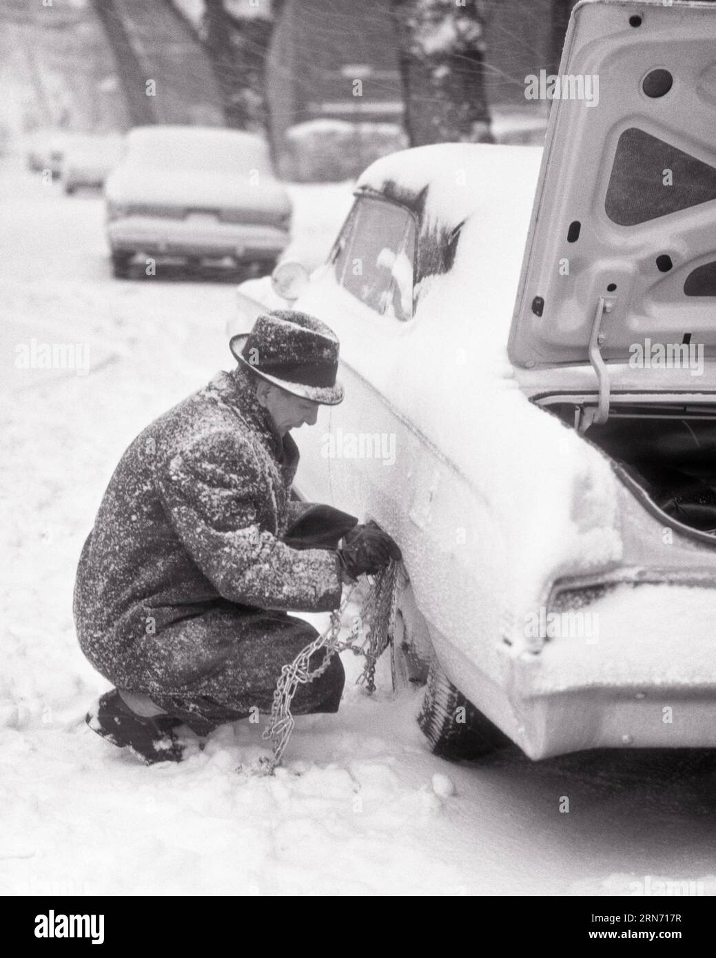 1960s MAN PUTTING CHAINS ON CAR TIRES DURING SNOW STORM - m6872 HAR001 ...