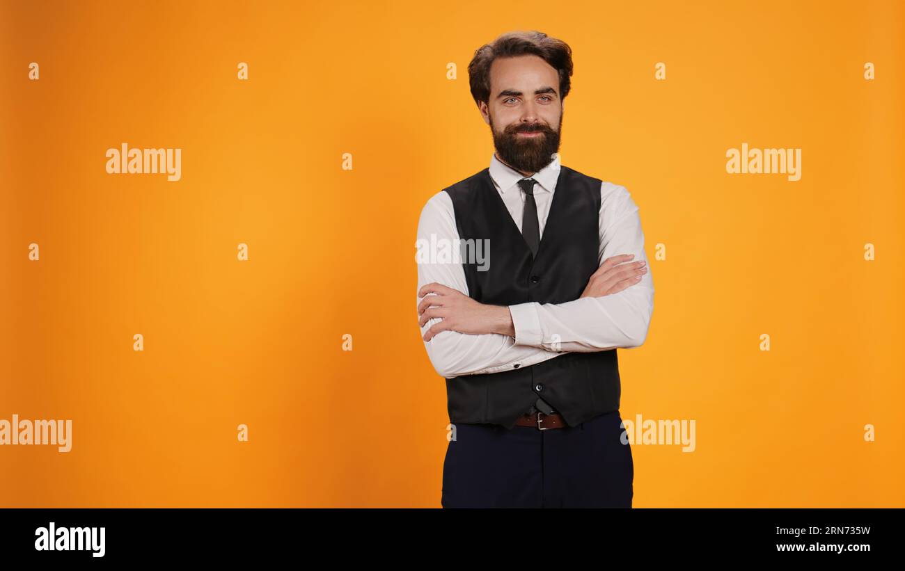 Refined waitstaff member poses happily in front of yellow background ...
