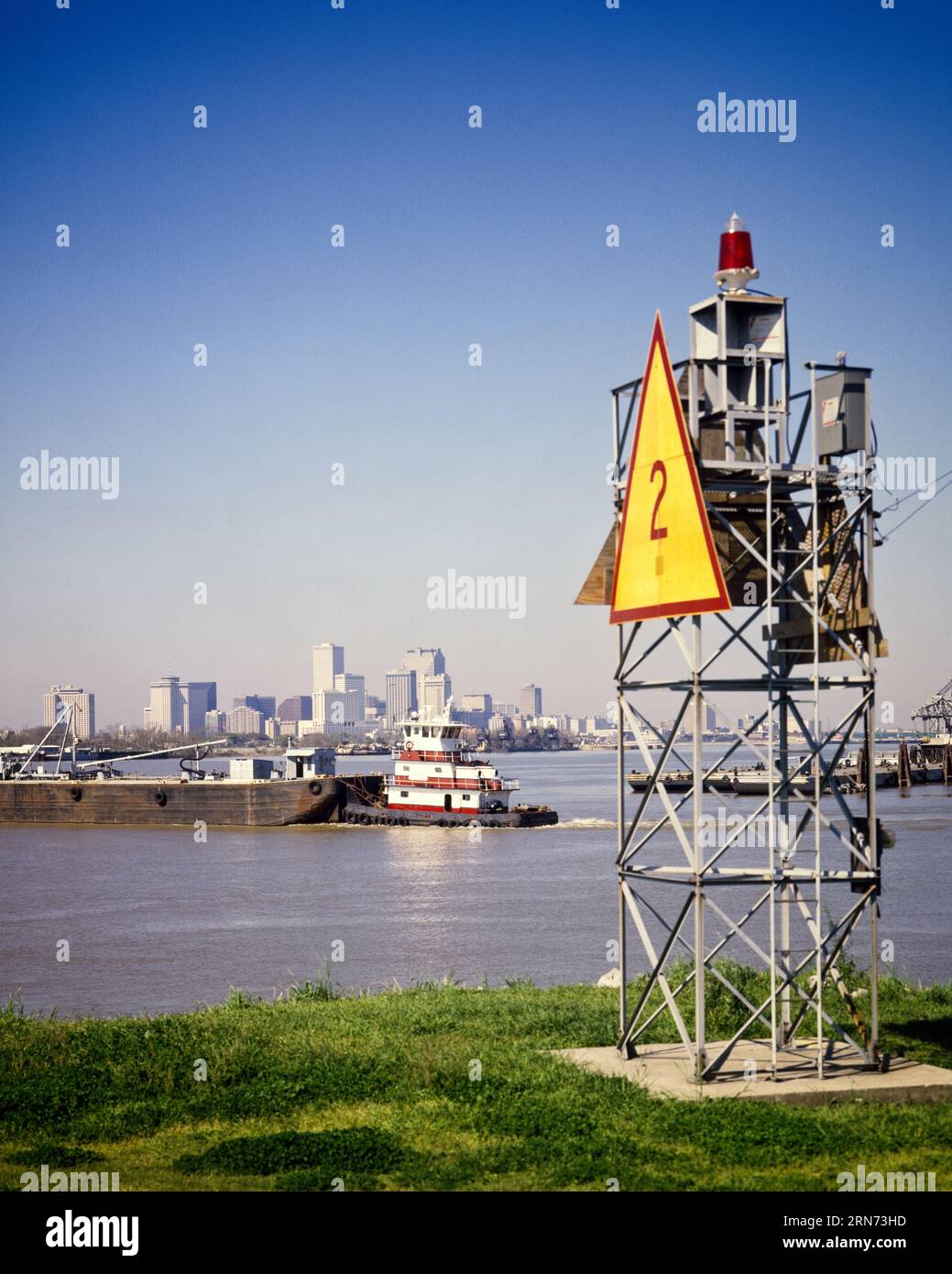 1990s TUG AND BARGE IN AN INDUSTRIAL CANAL WITH NAVIGATIONAL SIGNS AND ...