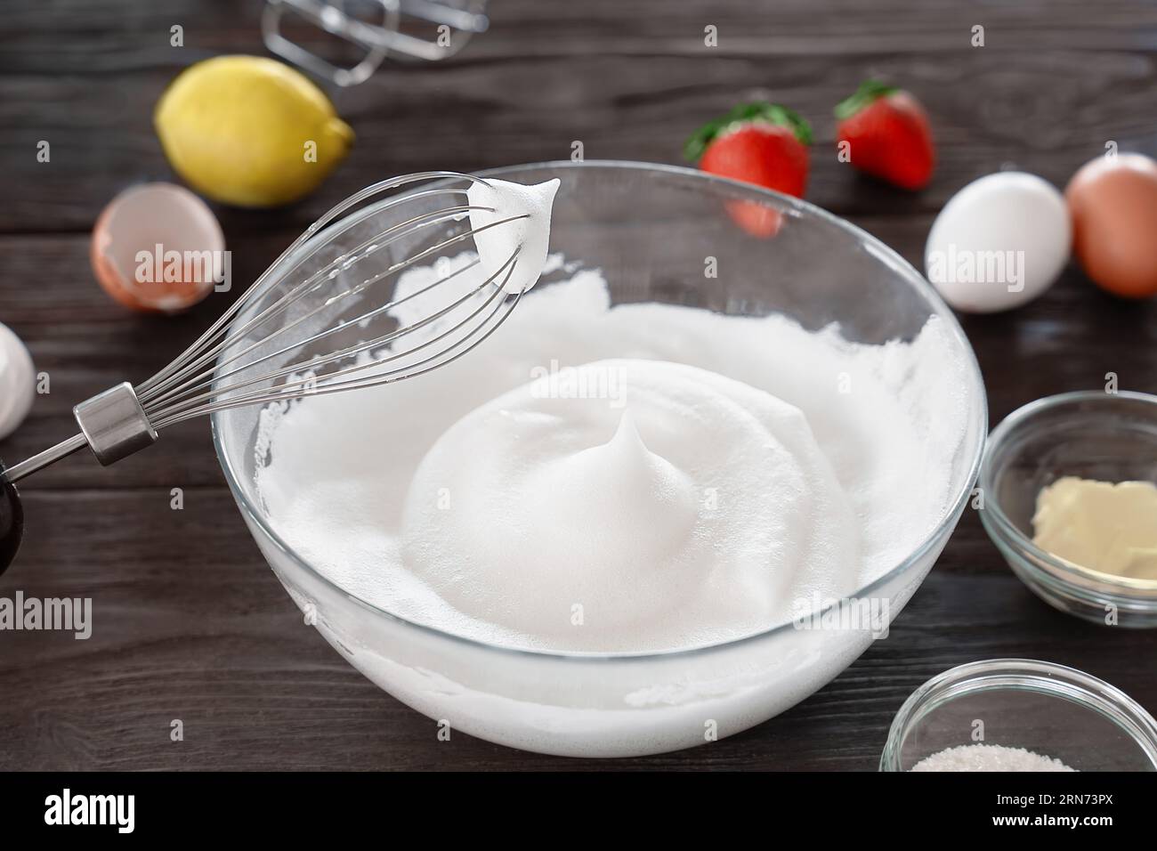 Close-up of a whisk and whipped egg whites to stiff peaks, a step in ...
