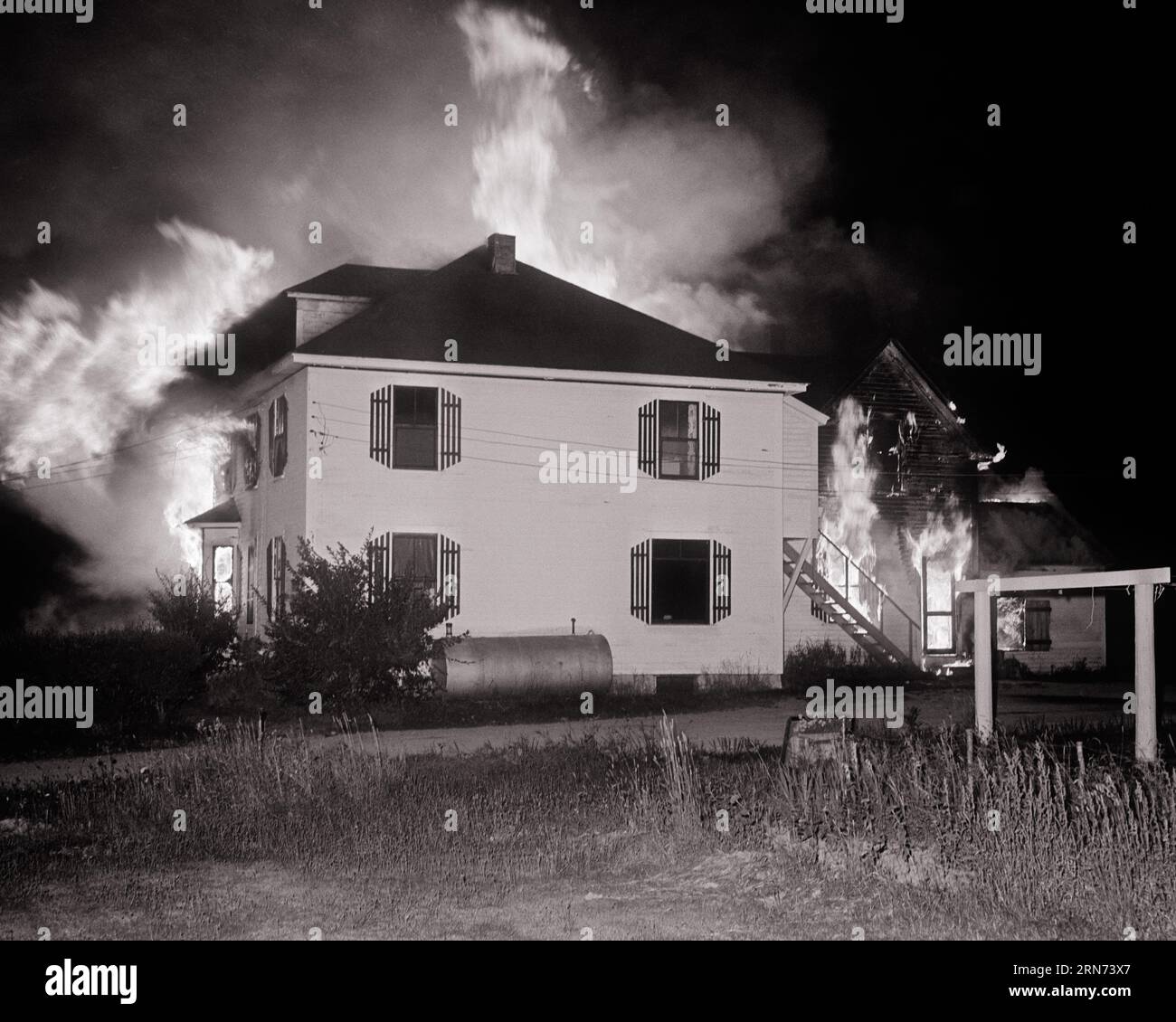 1960s TWO STORY HOUSE WITH SHUTTERS ON FIRE FLAMES BLAZING AT NIGHT NO ...