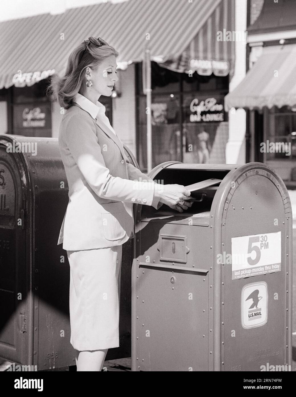 1970s WOMAN WEARING BUSINESS SUIT POSTING AN ENVELOPE IN SIDEWALK USPS ...