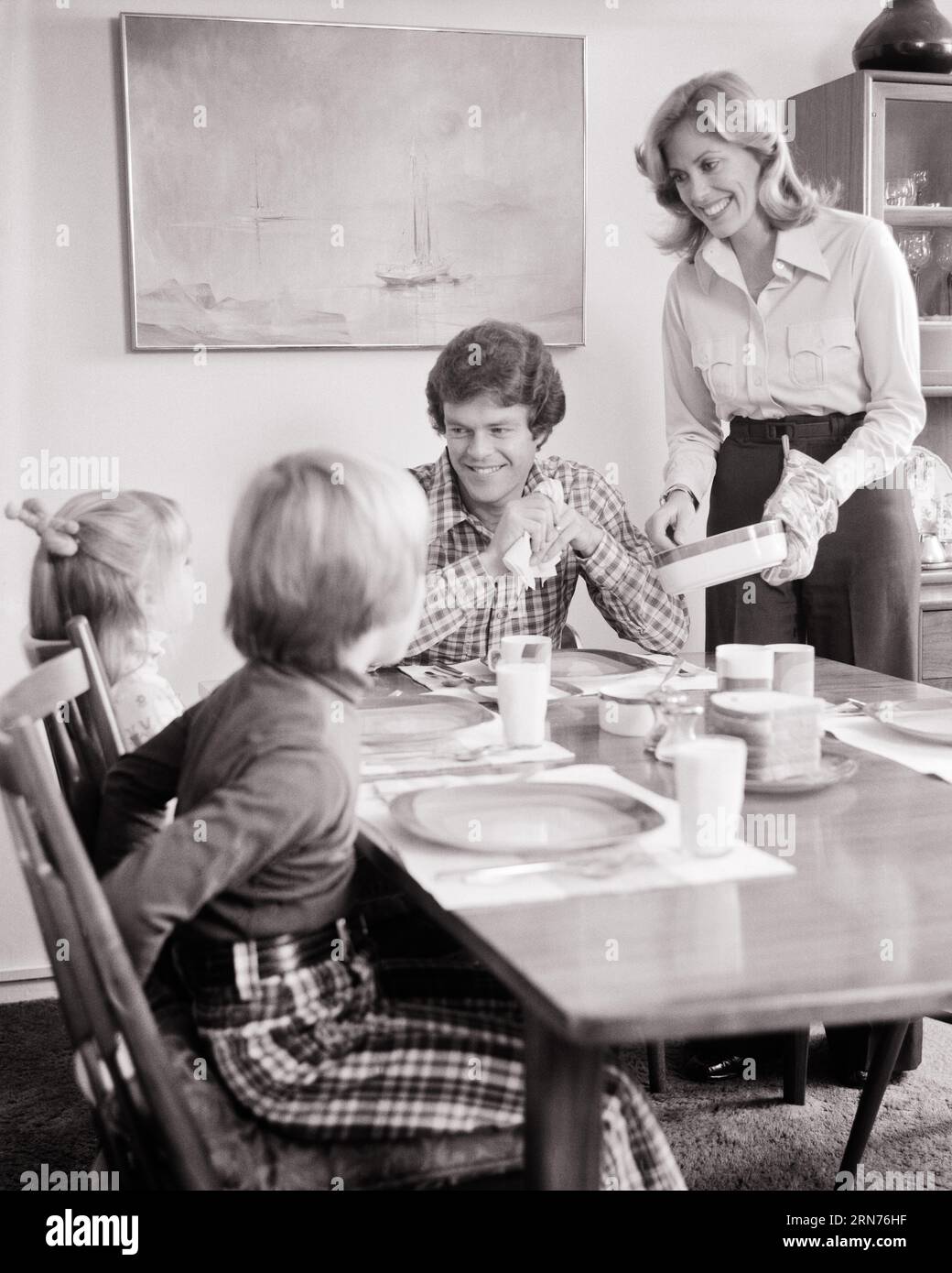 1970s FAMILY OF FOUR READY FOR MEAL SMILING MOTHER SERVING FATHER AND ...