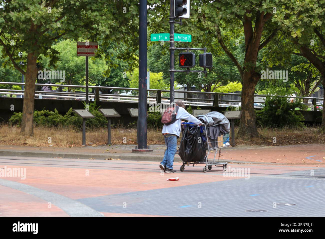 Homeless man pushing a shopping cart across the street in downtown ...