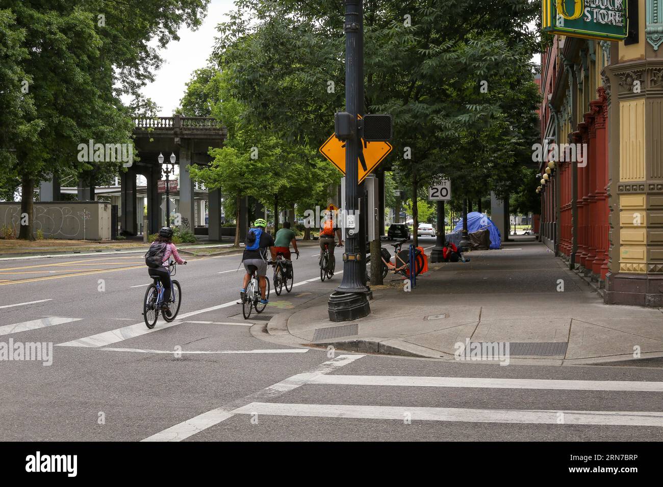 People riding their bikes past homeless people and tents in downtown ...