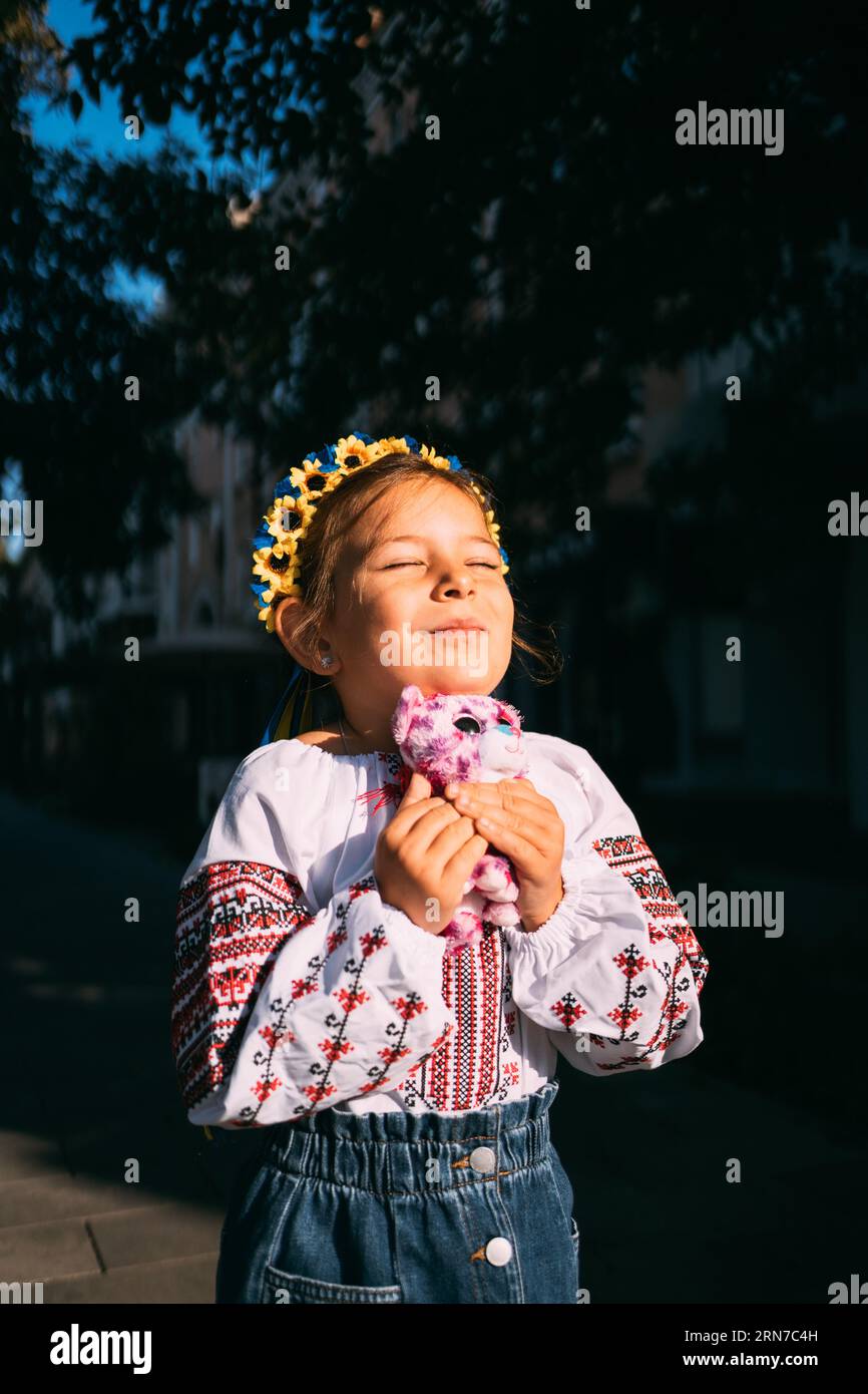Child girl in Ukrainian traditional clothes and flower wreath is ...