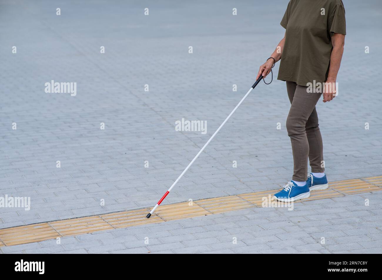 Close-up of the legs of an elderly blind woman with a cane at a tactile ...