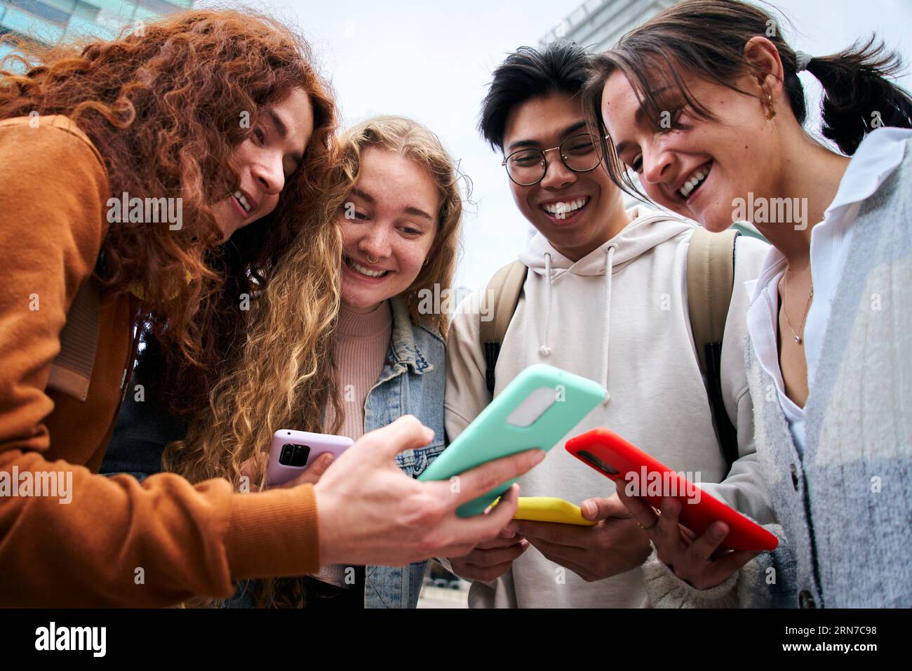 Group of multiracial classmate students looking at their smartphones ...