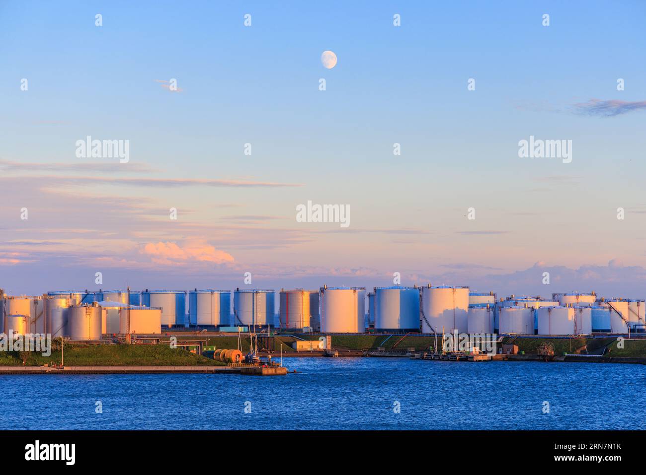 Moon over LNG storage tanks in port at sunset Stock Photo - Alamy