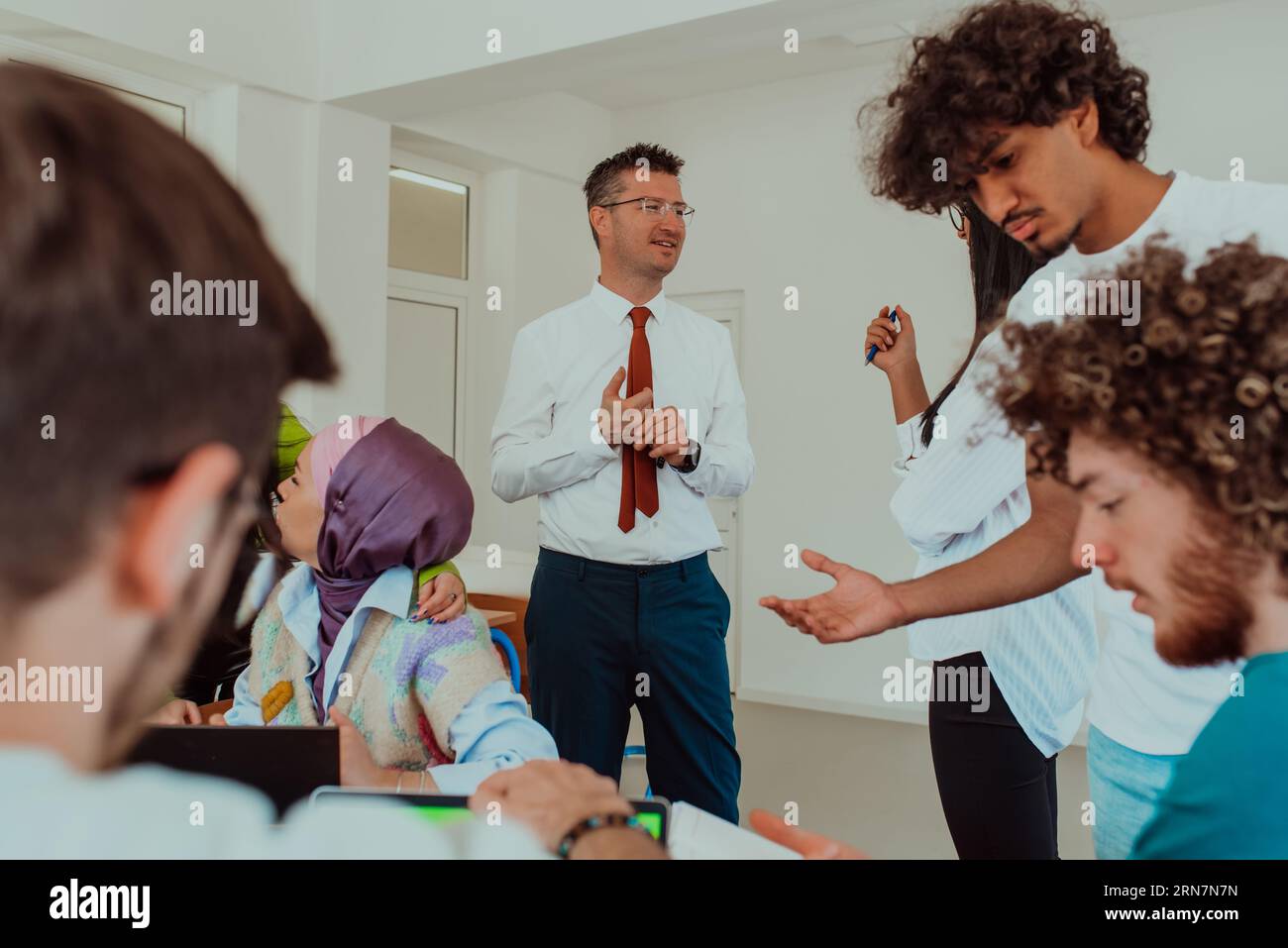 A modernly dressed professor engages in educating students, who listen ...