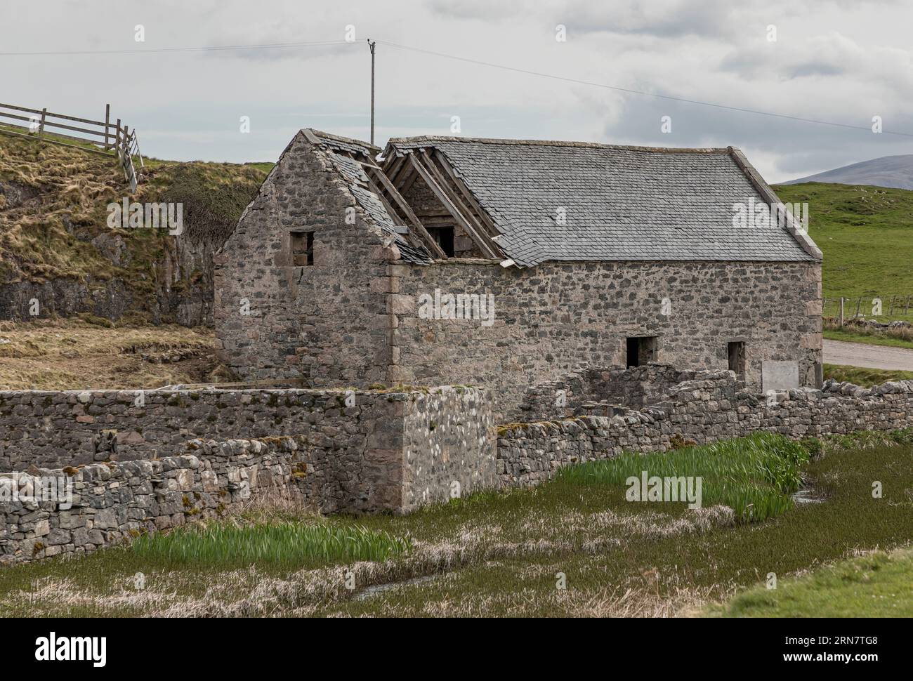Scottish barn with a broken collapsed roof against a grey stormy sky ...