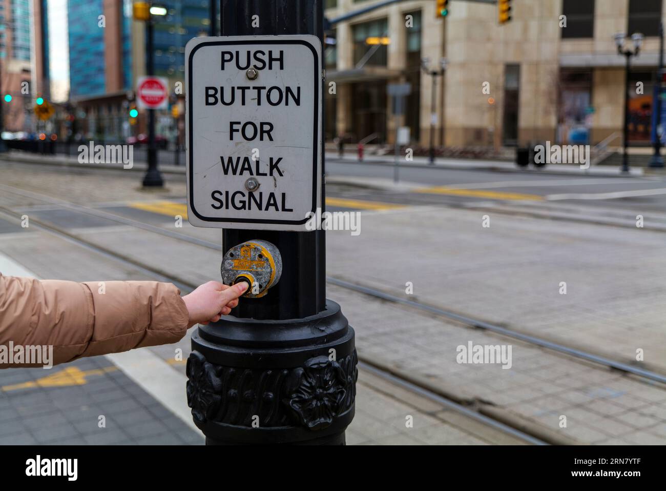 Woman hand on pedestrian sign and push button to cross railroad in ...