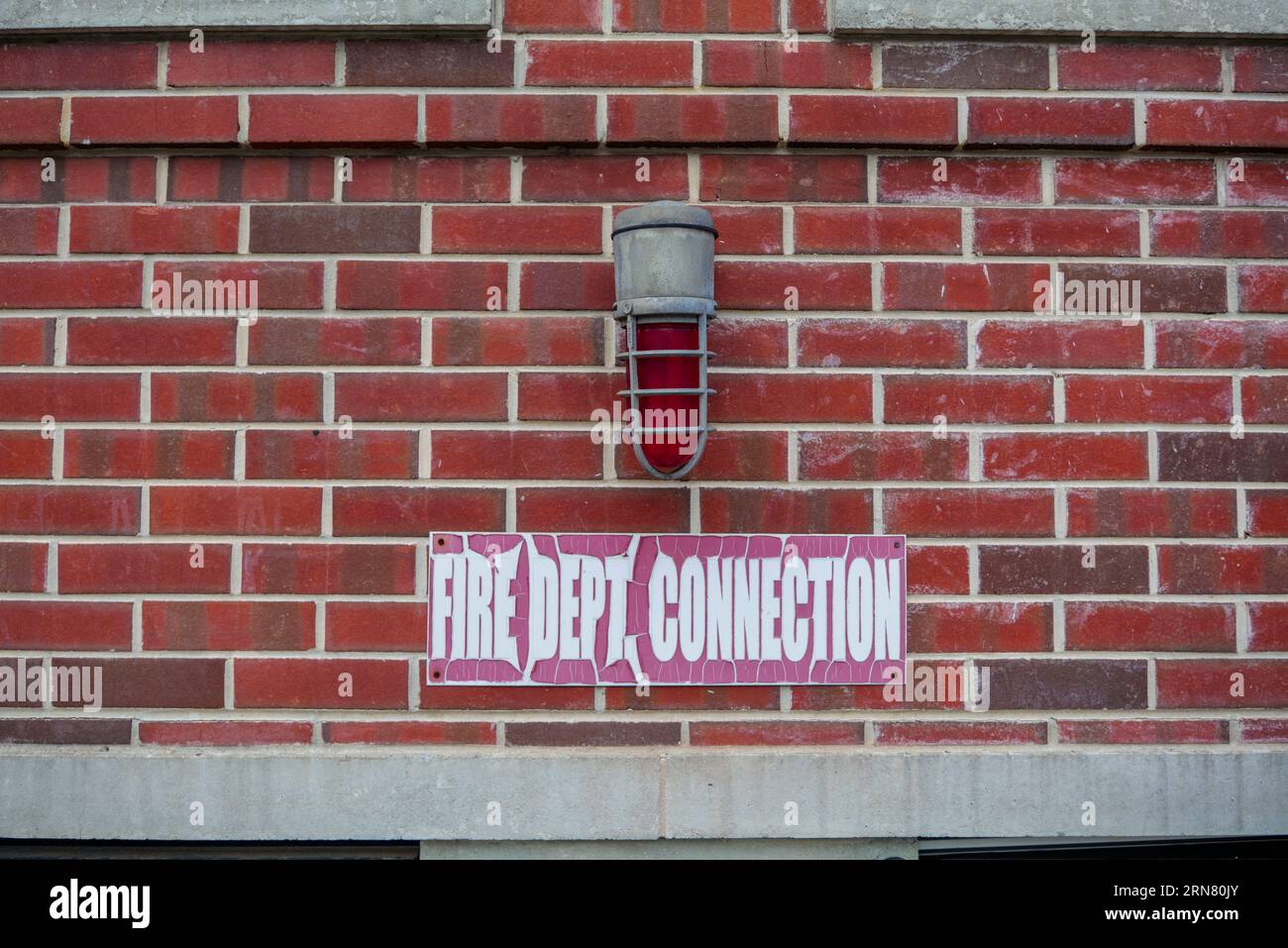 Fire department connection sign and red indicator lamp on brick wall ...
