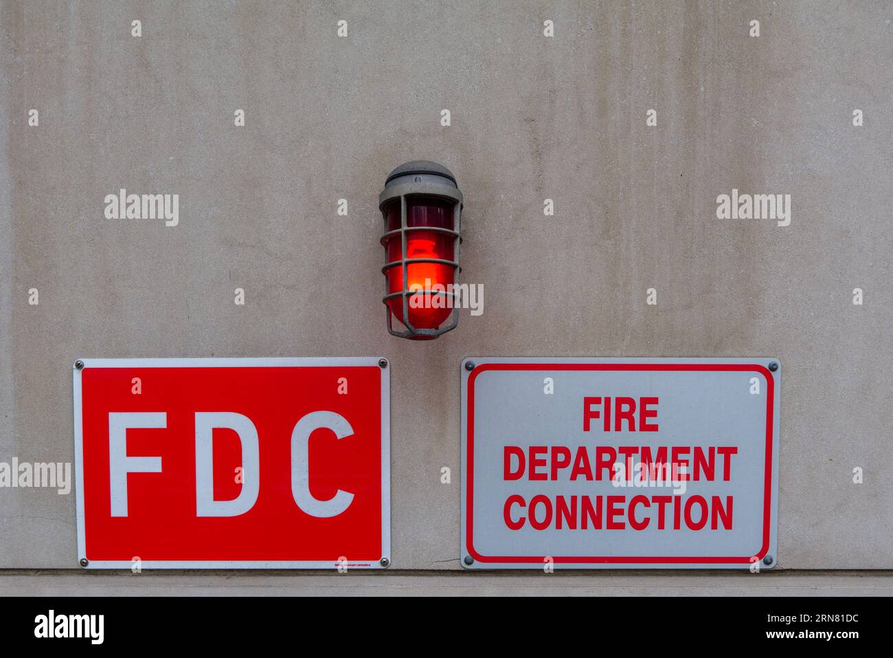 Fire department connection sign and red indicator lamp on brick wall ...