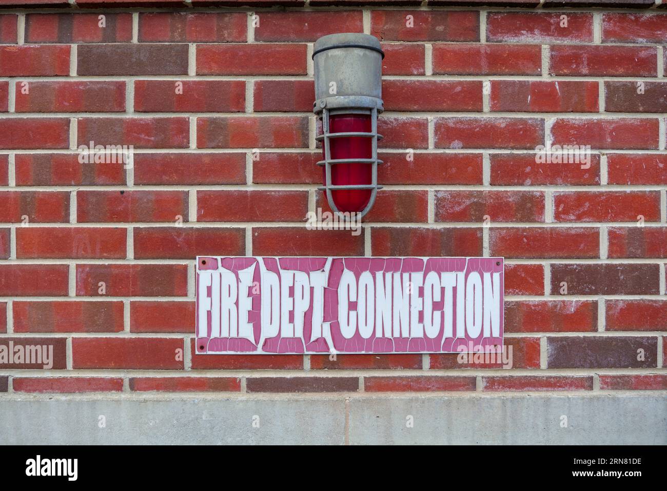 Fire department connection sign and red indicator lamp on brick wall ...