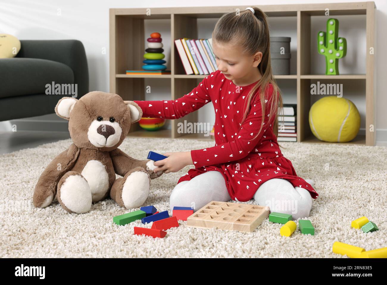 Cute little girl playing with teddy bear and cubes at home Stock Photo ...