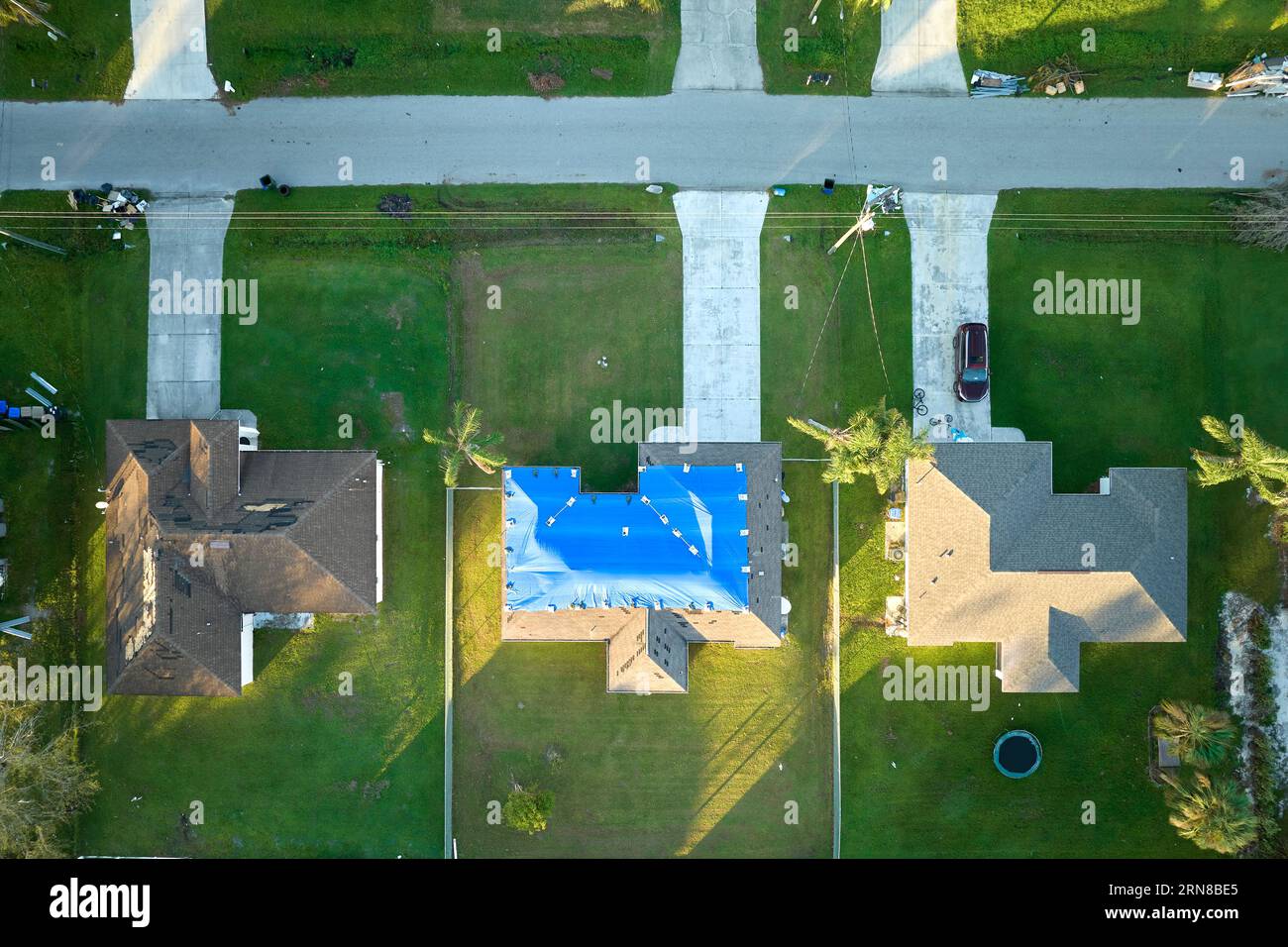 Aerial view of damaged in hurricane Ian house roof covered with blue ...