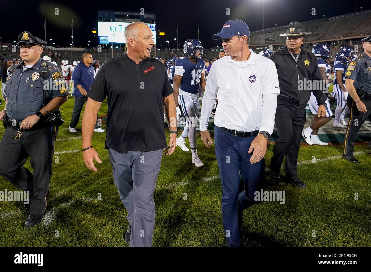 UConn head coach Jim Mora, front right, walks off the field with North ...