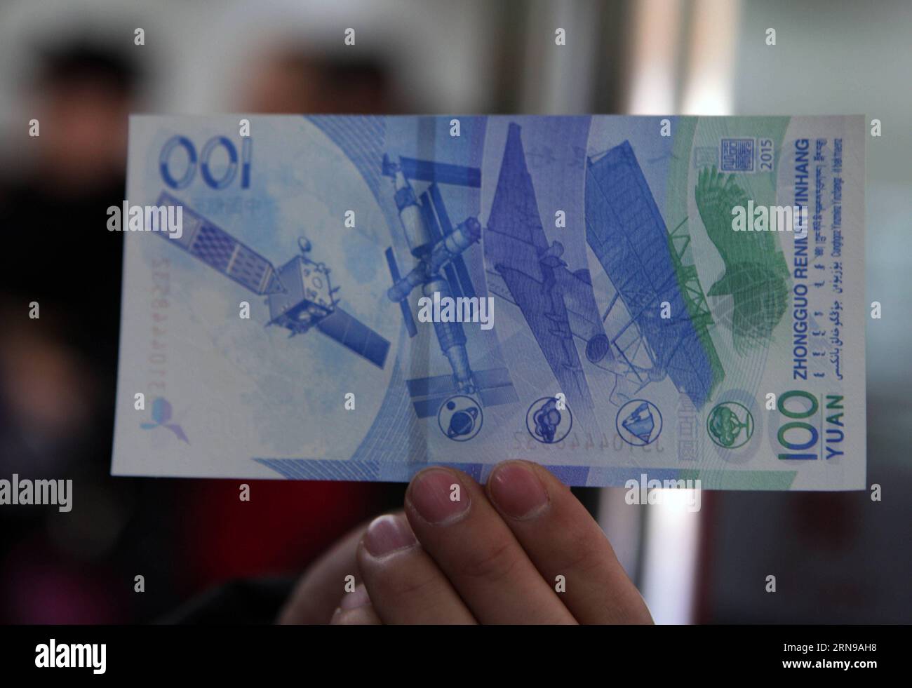A resident shows a commemorative note at a bank in Beijing, capital of ...