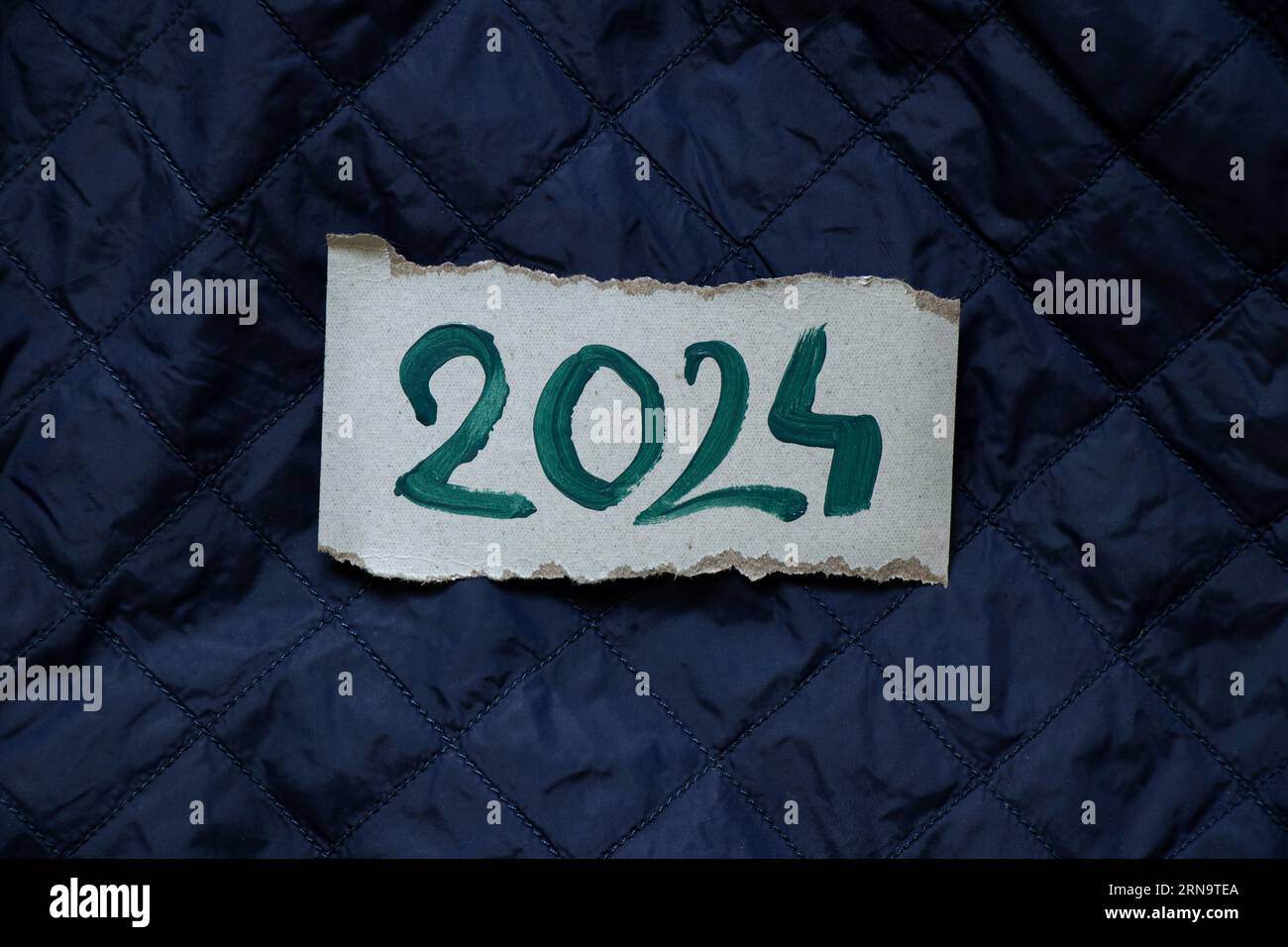 2024 is written in green ink on a paper card lying on a blue quilted ...