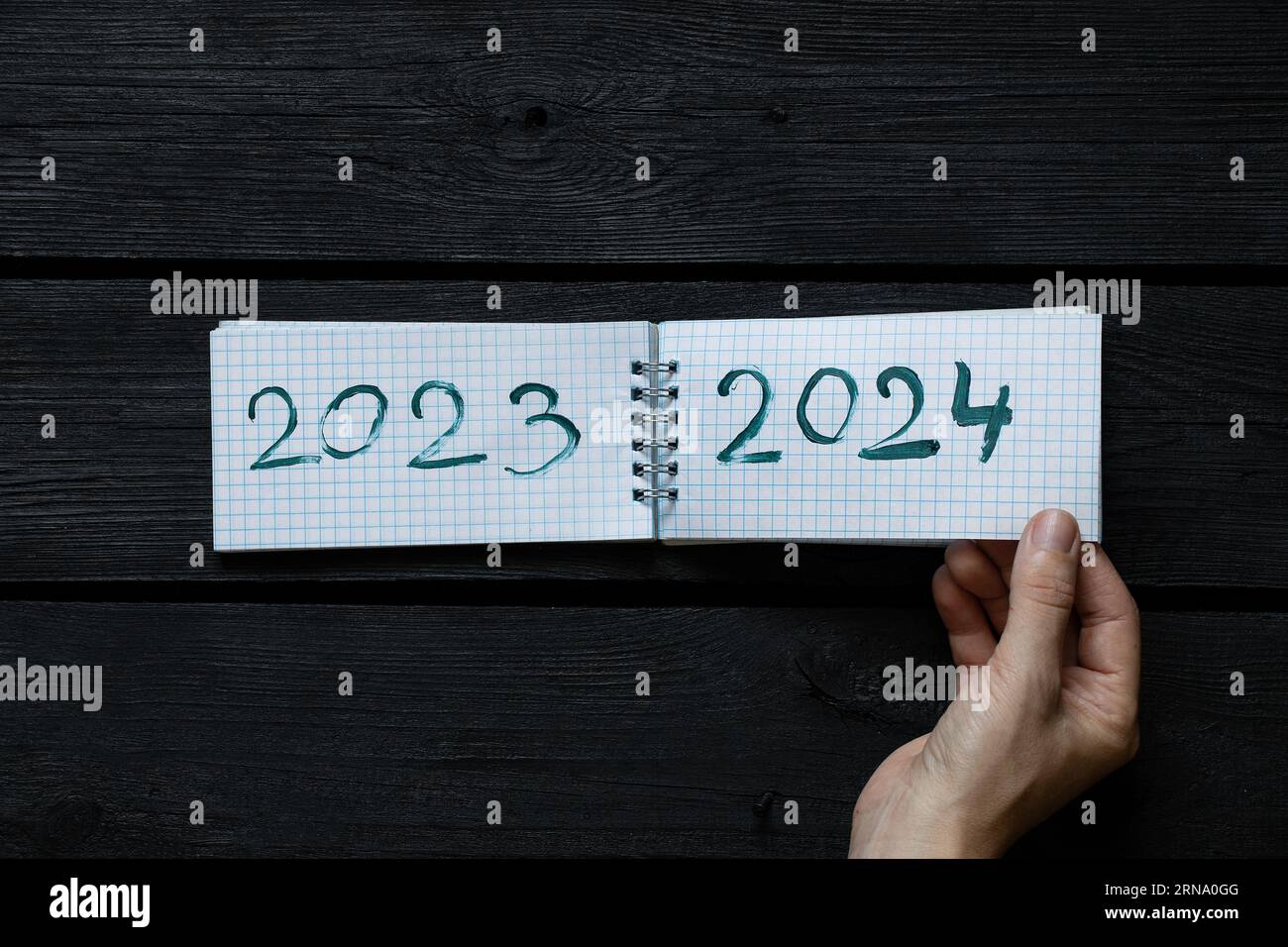 Notepad with the text 2023 and 2024 drawn with paint and a woman's hand ...