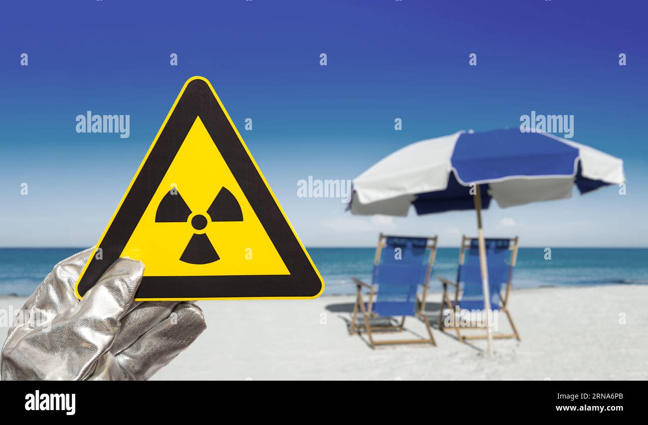 nuclear radiation warning sign in front of blurred sun loungers and ...
