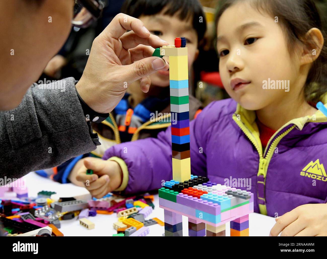 Children watch a participant competing in the LEGO Master Model Builder ...