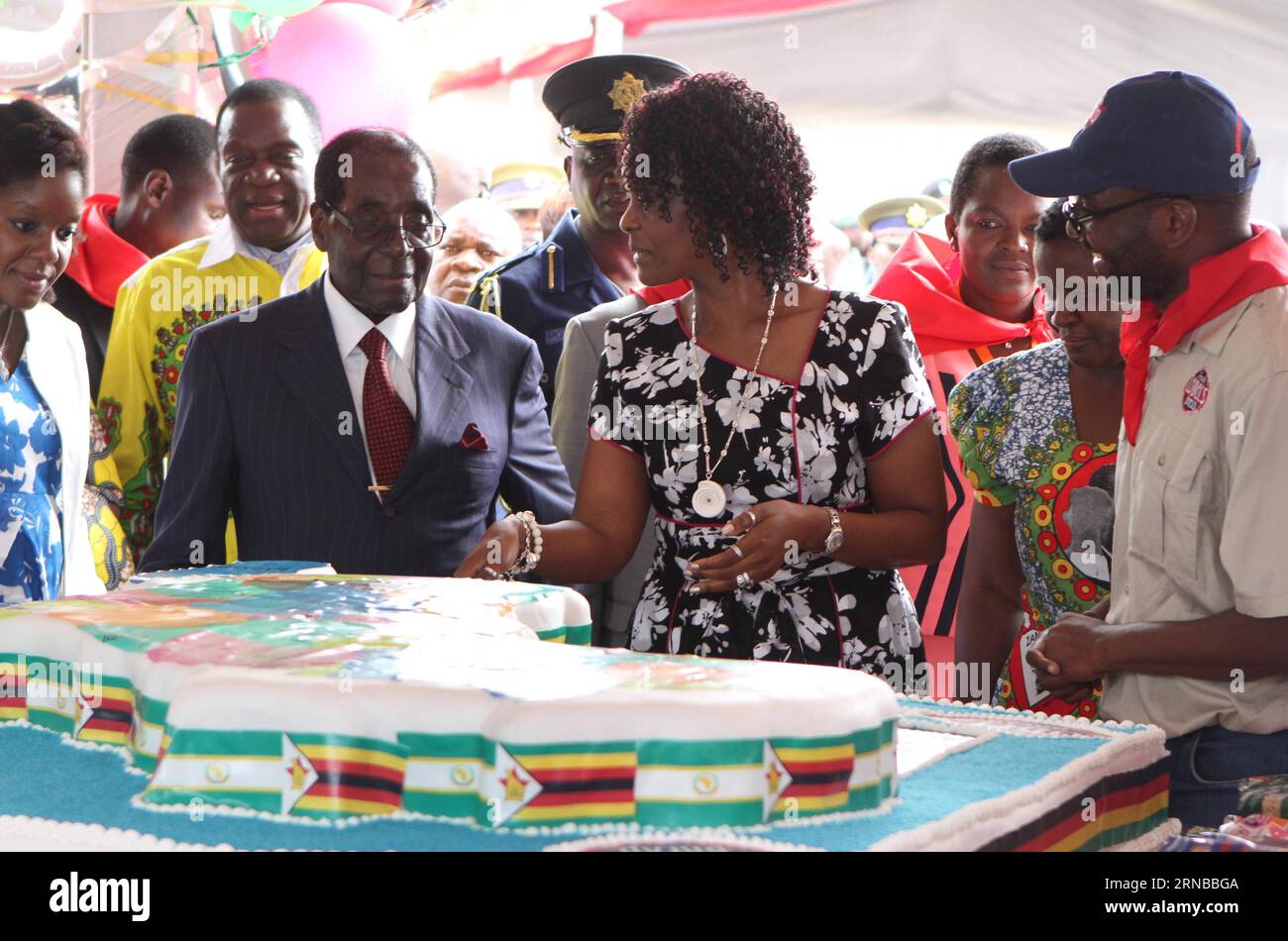Zimbabwean President Robert Mugabe is helped to cut the cake by his ...