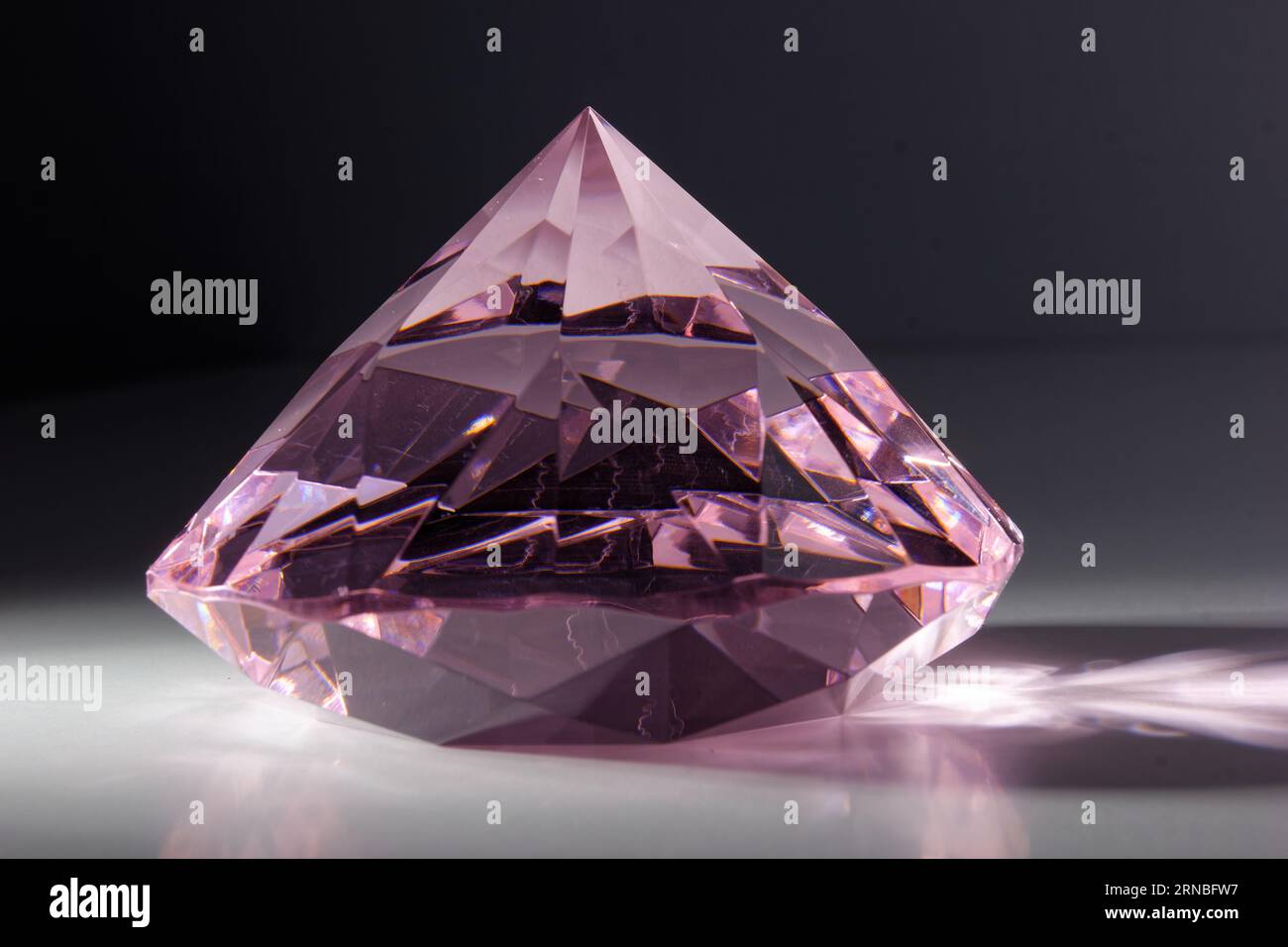 real glass object with shadows formed as diamond on white table with ...