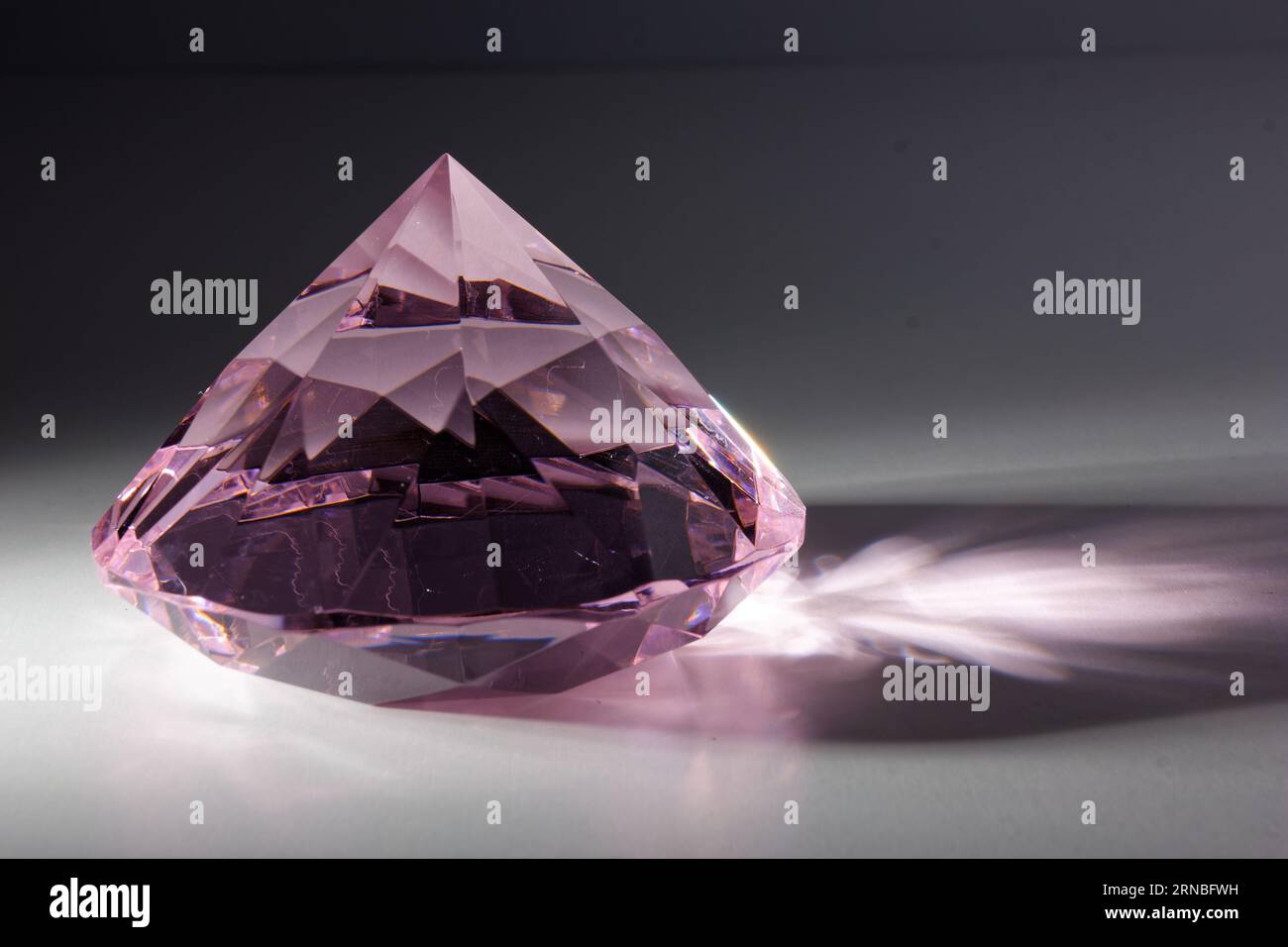 real glass object with shadows formed as diamond on white table with ...