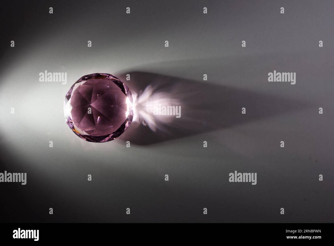 real glass object with shadows formed as diamond on white table with ...