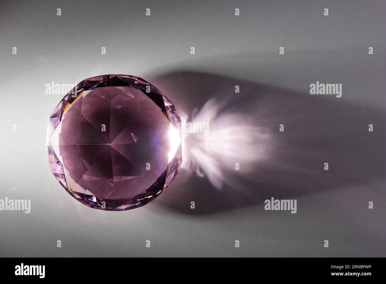 real glass object with shadows formed as diamond on white table with ...